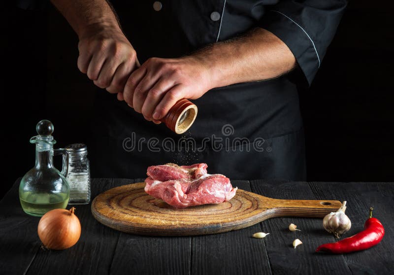 Professional Chef Cooking Raw Meat Fillet and Adding Pepper or Chili ...
