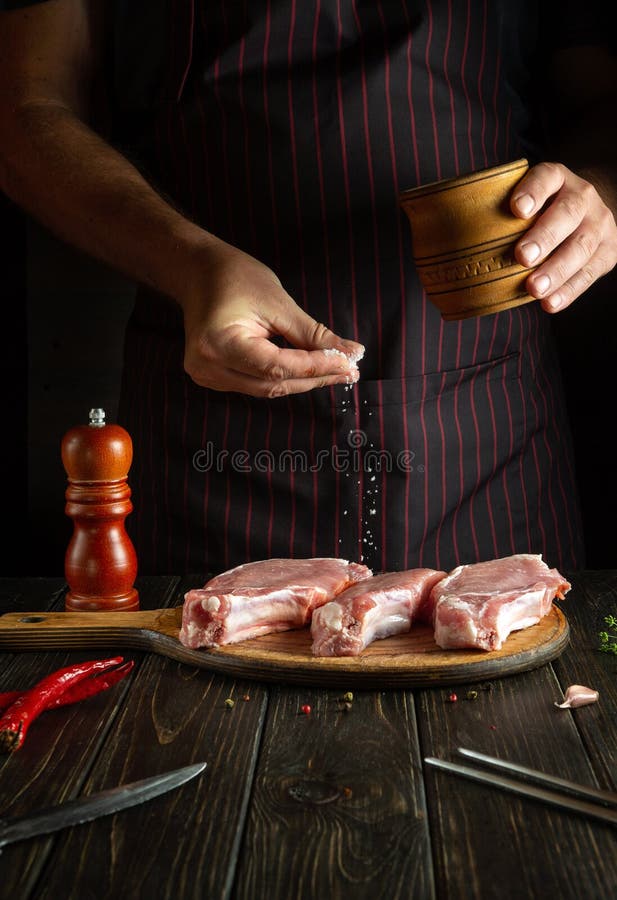 Professional Chef Salts Raw Sliced Meat Steaks on the Cutting Board of ...