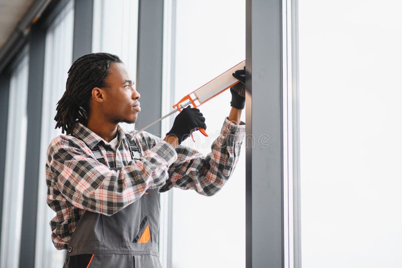 African American Construction Worker Applying Sealant To Window Frame ...