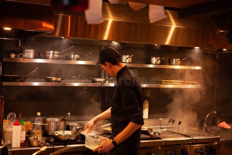 Professional Cook. Chef in Black Apron and Cap Working in Restaurant ...