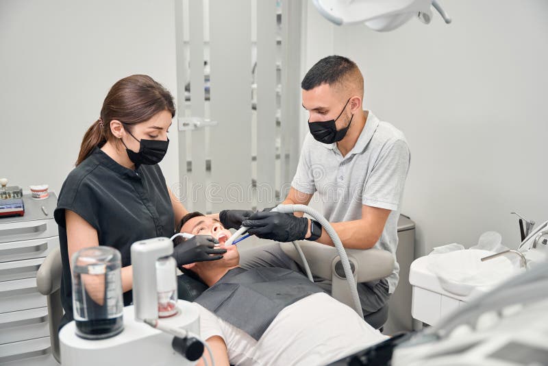 Professional Dentist Team Working on Male Client Tooth Treatment Stock ...
