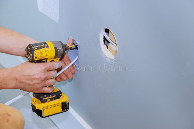 Professional Electrician Installing an Electric Socket in Wall of a ...