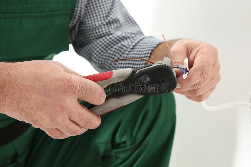 Electrician is Stripping Electrical Wires in a Plastic Box on a Wooden ...