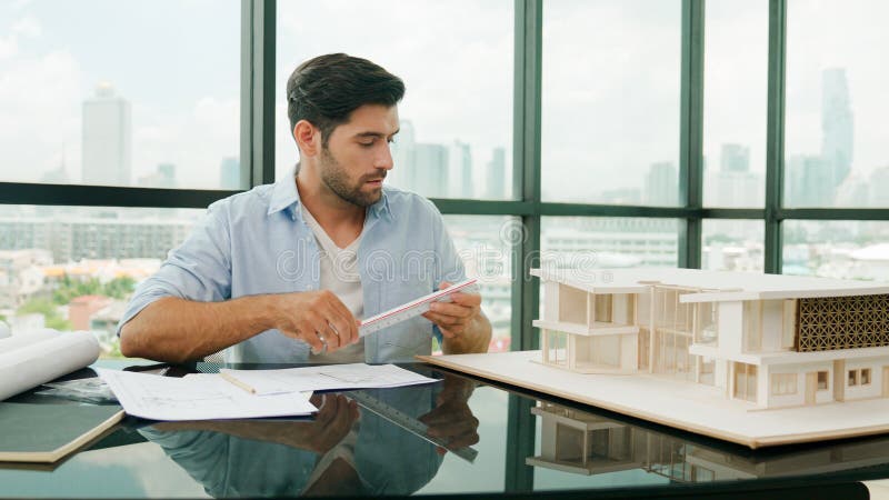 Skilled Engineer Looking at Blueprint while Measure House Model ...