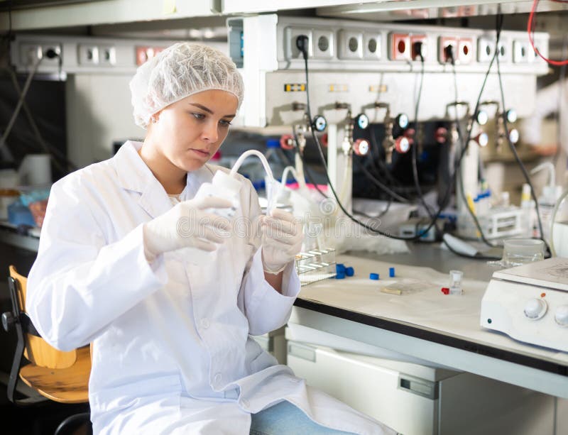 Professional Female Chemist Investigating Behavior of Blue Liquid ...