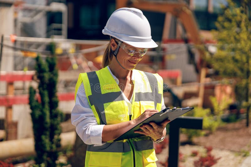 Professional Female Engineer in Protective Helmet Making Notes on ...