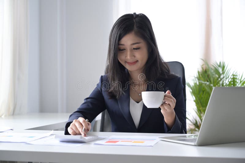 Financial Advisor Drinking Coffee and Checking Reports at Office Desk ...