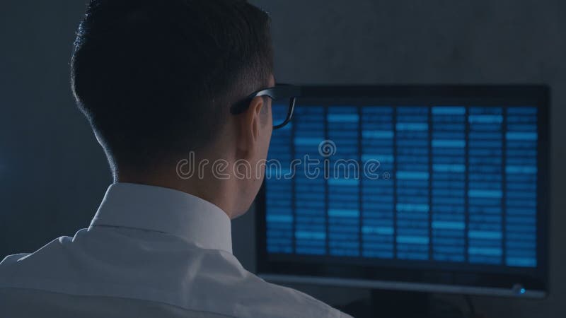 Professional it Geek Programmer in Glasses is Working on Computer with Binary Code at Night ...