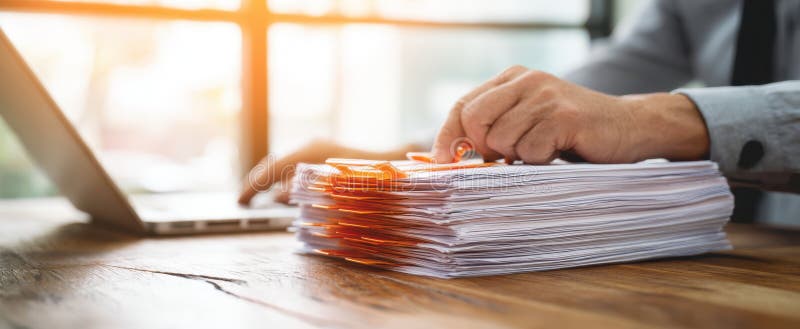 The Professional Handling Paperwork while Working on a Laptop in an ...