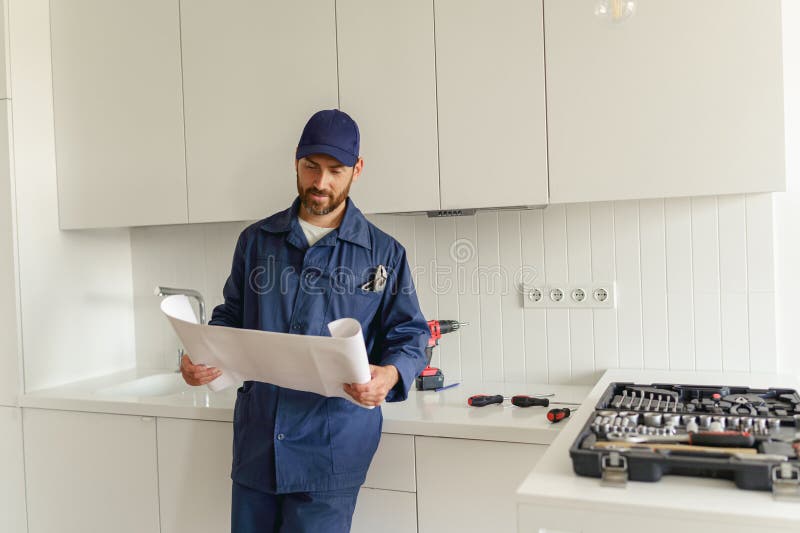 Male Worker in Uniform Standing on Kitchen with Home Plan before ...