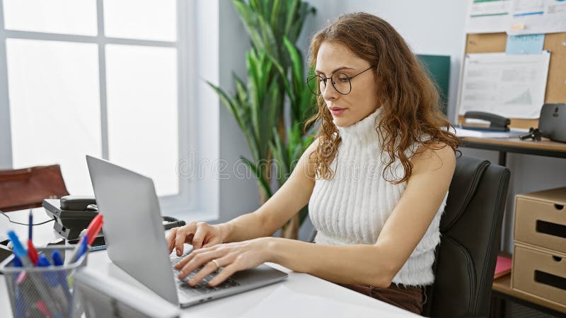 A Professional Hispanic Woman Focused on Working at Her Laptop in a ...