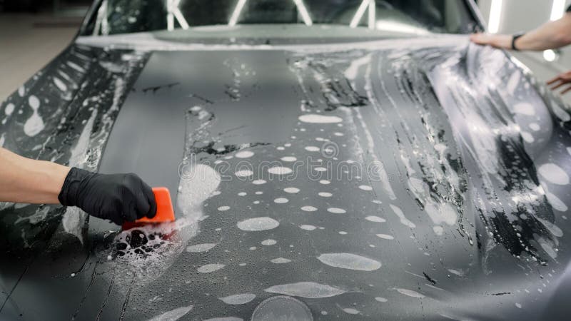 Professional Installing Protective Film on Car Hood Using Squeegee and ...