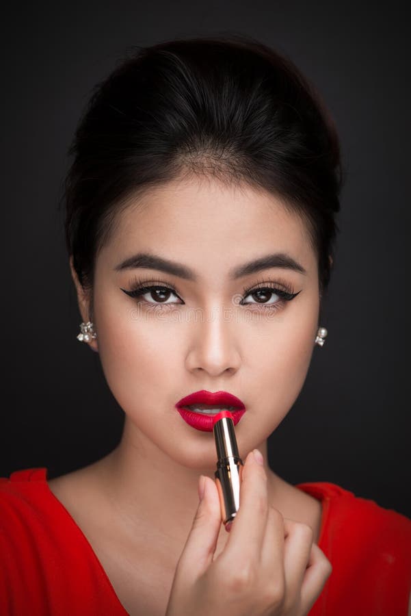 Professional Make-up. Attractive Asian Model Applying Red Lipstick ...