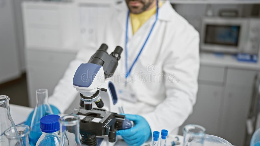 Professional Man in Lab Coat Using Microscope in a Laboratory Setting ...