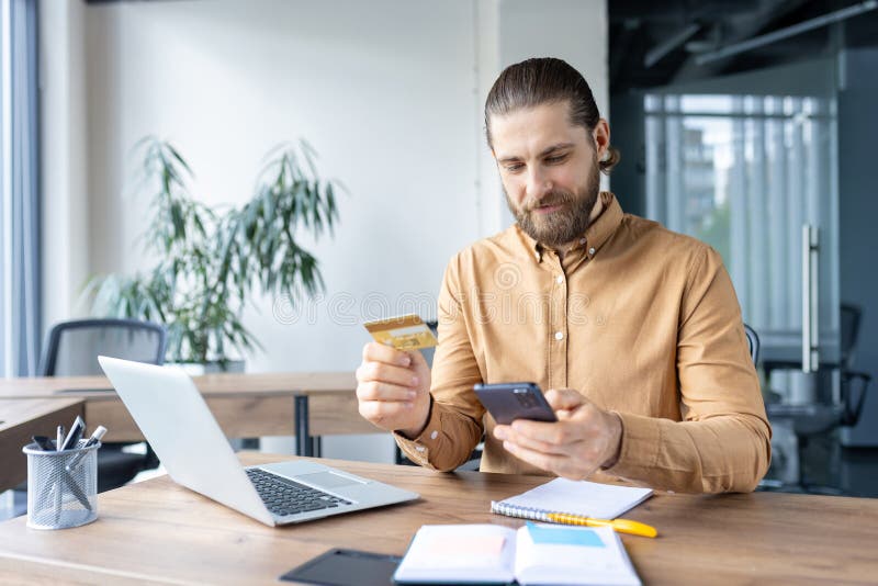 Man Shopping Online with a Phone and Credit Card in Modern Office Stock ...