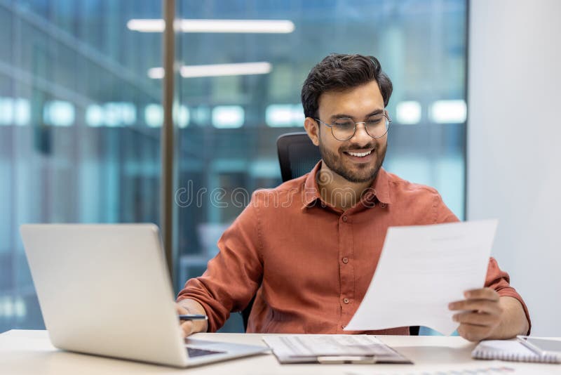 Professional Man Reading Document at Modern Office Desk with Laptop and ...