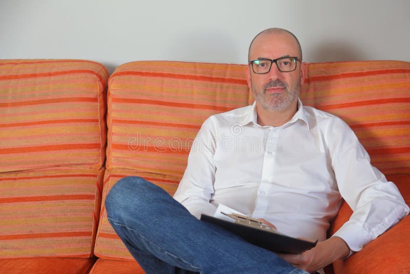 Professional Man Sitting on Couch Holding Clipboard in Comfortable ...