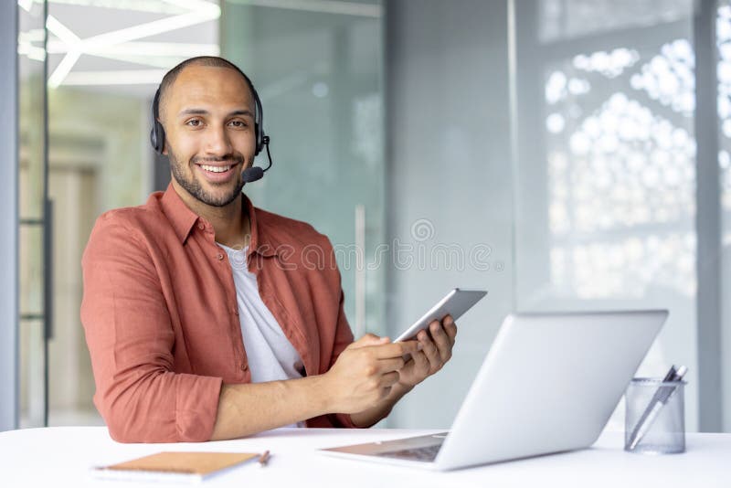 A Professional Man Using a Headset and Tablet, Providing Support in a ...