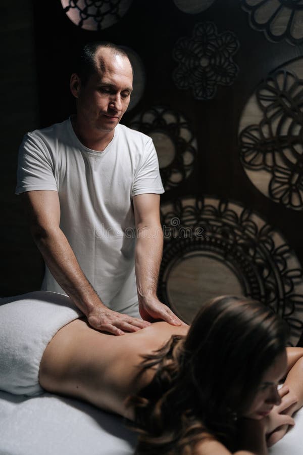 Professional Masseur Giving Back Massage To Female Client Lying On