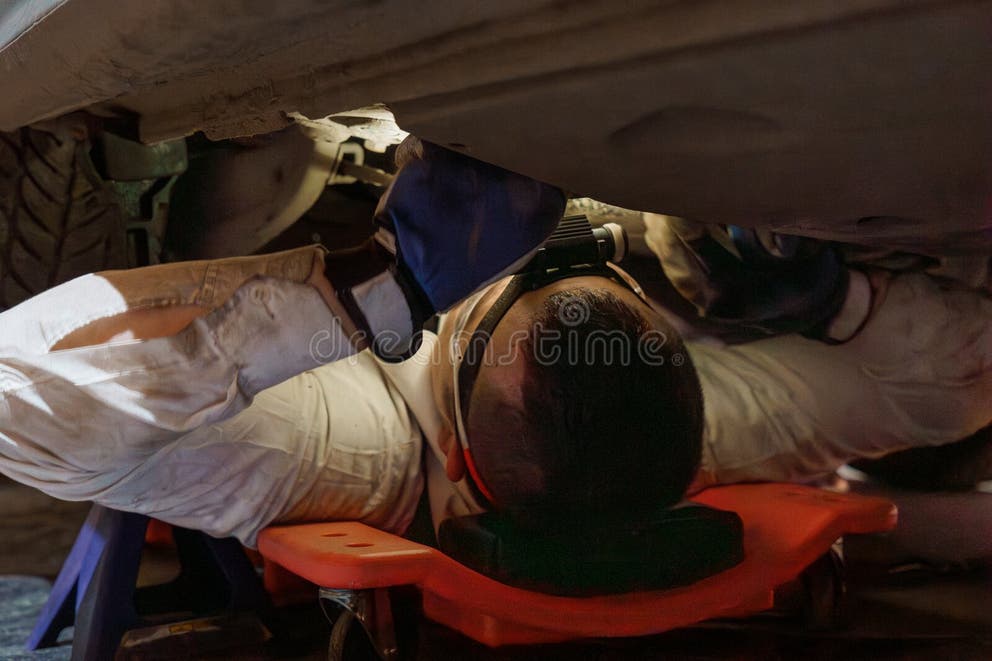 Professional Mechanic Inspecting Underside of Vehicle Using Flashlight ...