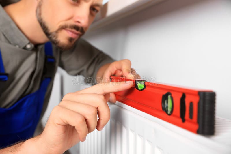 Professional Plumber Using Bubble Level for Installing New Heating ...