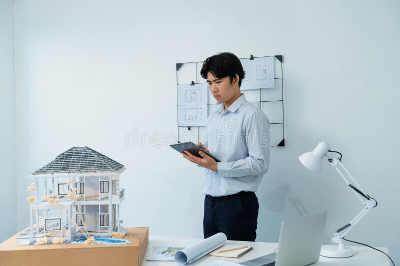 Architect Measures House Model Length while Colleague Using Laptop ...