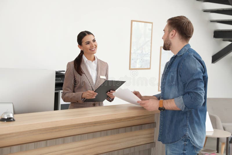 Professional Receptionist Working with Client at Desk Stock Photo ...