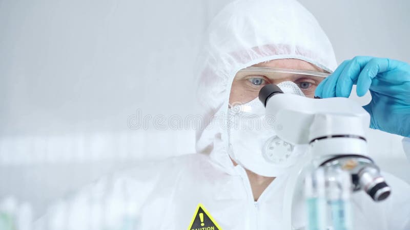 Professional Scientist in Protective Gear is Using Microscope in a ...