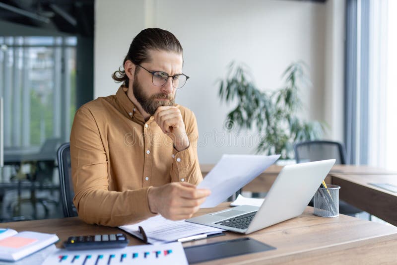 Focused Professional Reviewing Documents at Their Desk in Modern Office ...