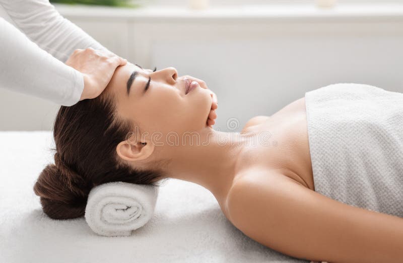 Professional Therapist Making Relaxing Head And Face Massage For Young