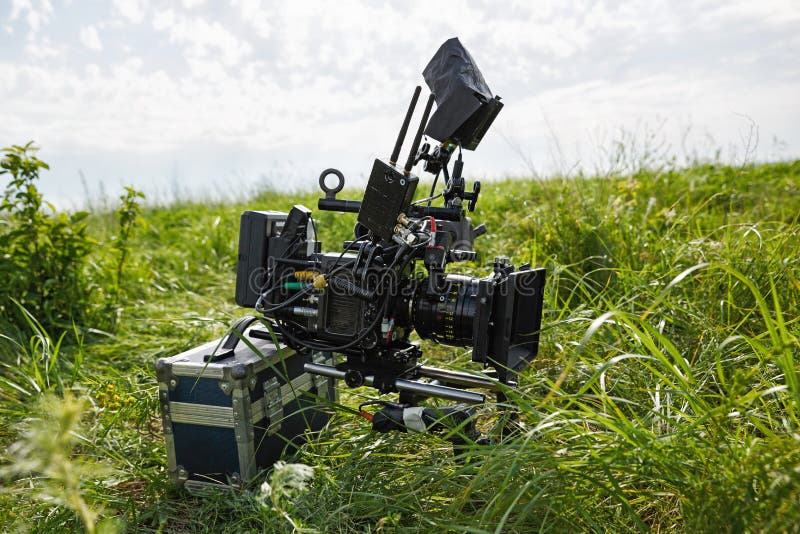 Professional Video Camera Lying on the Grass with a Suitcase for Optics ...