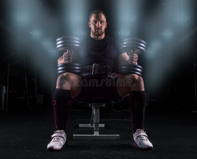 Professional Weightlifter Sits on a Bench with Two Dumbbells on Stock ...