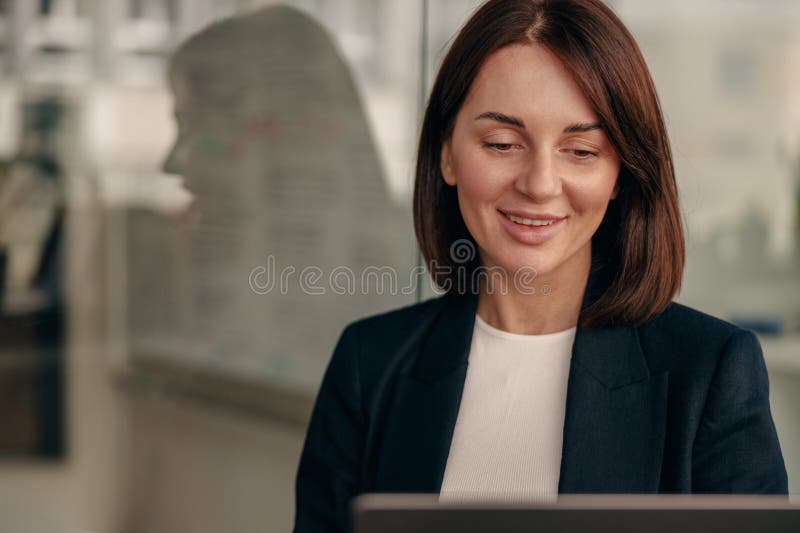 A Professional Woman is Focused on Her Work, Using a Laptop in an ...