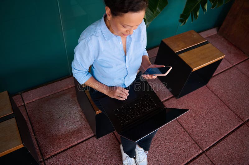 Professional Woman Multitasking with Laptop and Smartphone in Modern ...