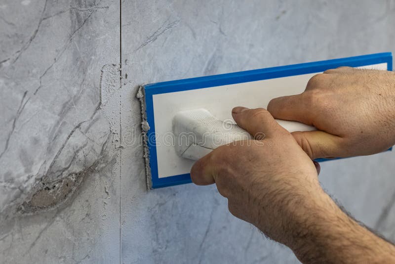 Professional Worker Applying Grout on Ceramic Tile Wall with a Rubber ...