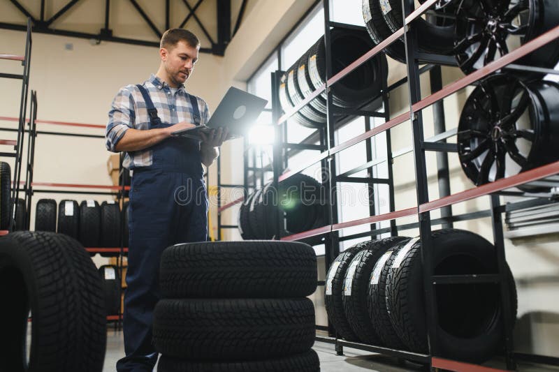 Professional Worker with Tire. Man is in the Tire Fitting Car Service ...