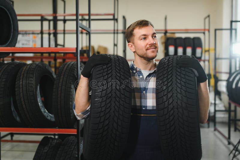 Professional Worker with Tire. Man is in the Tire Fitting Car Service ...