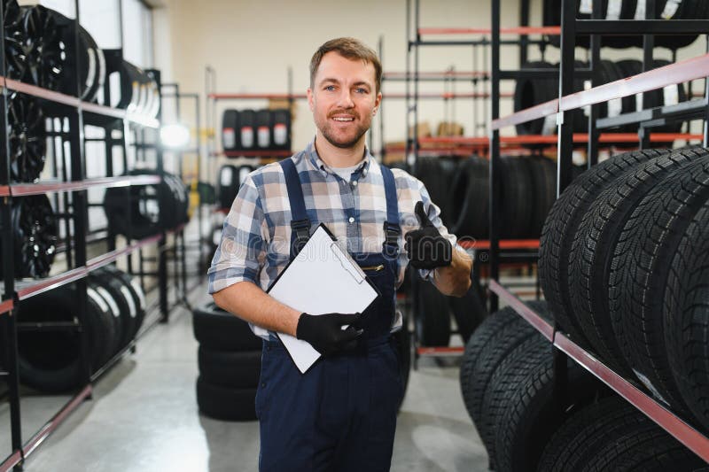 Professional Worker with Tire. Man is in the Tire Fitting Car Service ...