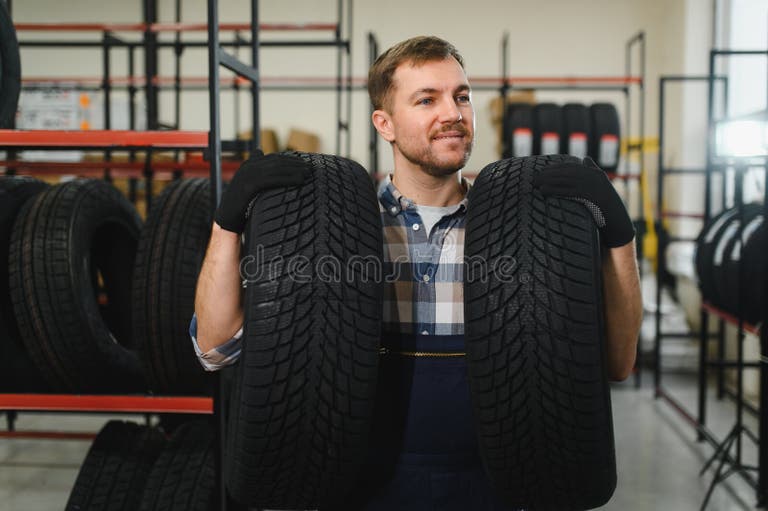 Professional Worker with Tire. Man is in the Tire Fitting Car Service ...