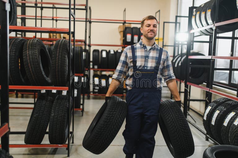Professional Worker with Tire. Man is in the Tire Fitting Car Service ...