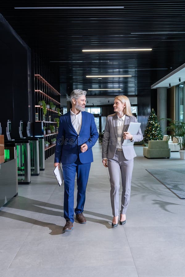 Professional Workers Going through Corridor Talking about Company ...