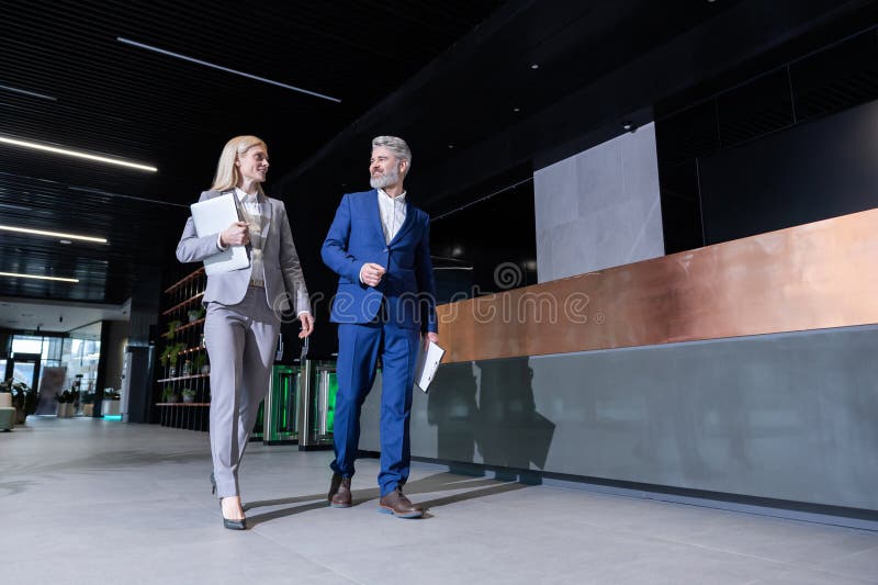 Professional Workers Going through Corridor Talking about Company ...