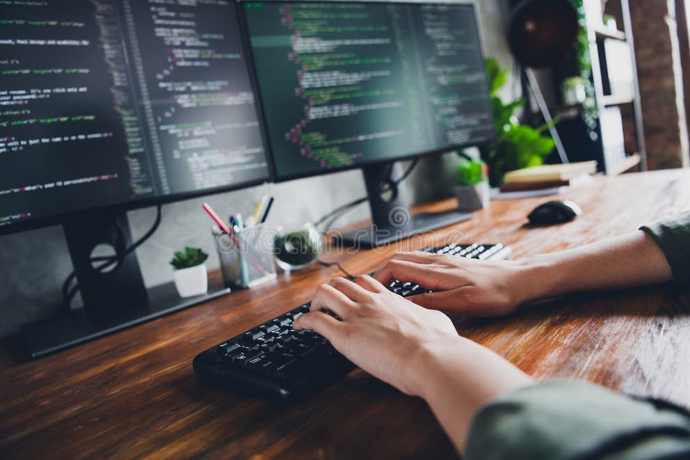Young Female Programmer Working with Code on Dual Monitors in a Stylish Workspace, Symbolizing ...
