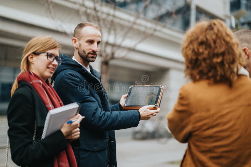 Professionals Collaborating and Reviewing Data on a Tablet Outdoors ...