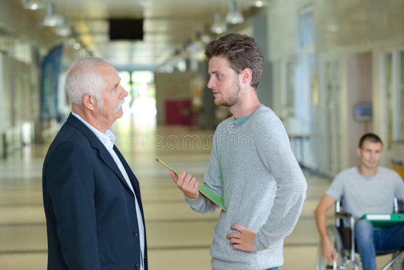 Professor with Notebook Talking To Student in Corridor Stock Photo ...