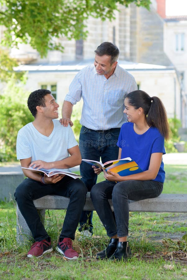 Professor Saying Hello To Students Reviewing on Bench Stock Image ...