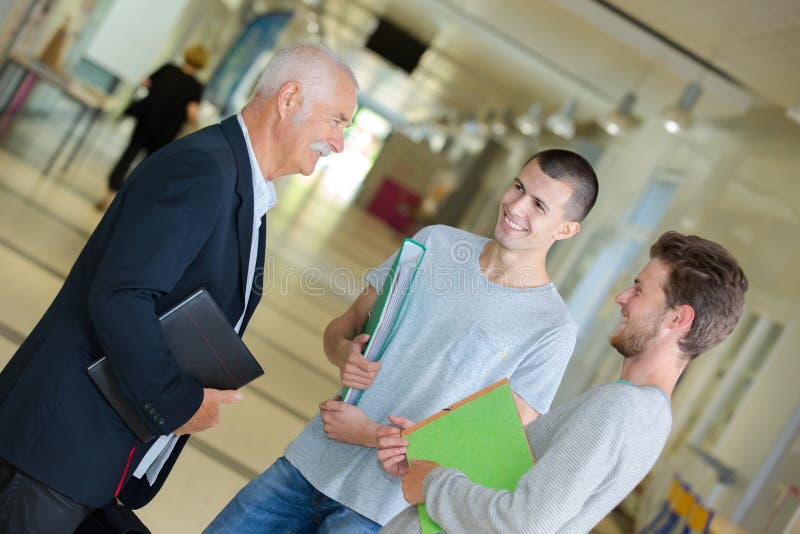 Professor Talking To Students in Hallway Stock Image - Image of subject ...
