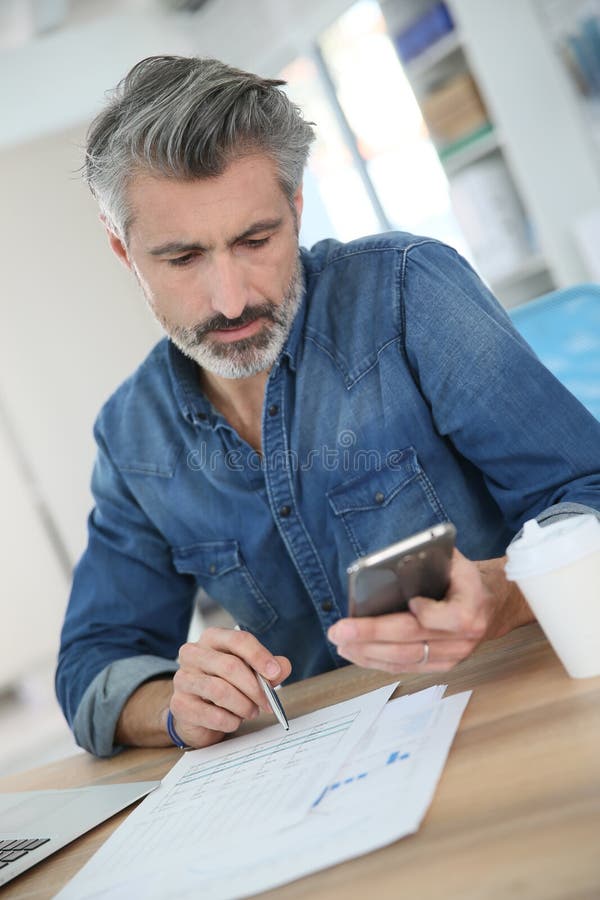 Professor Using Laptop and Smartphone in School Office Stock Photo ...