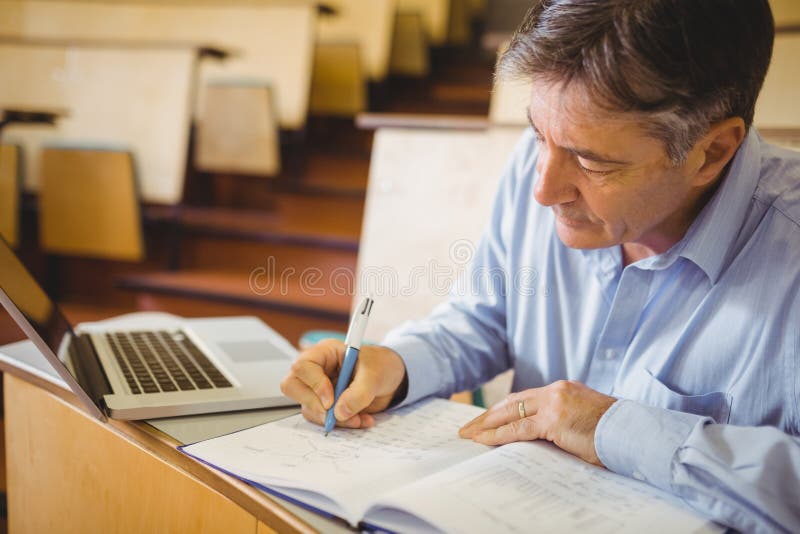 Professor Writing in Book at Desk Stock Photo - Image of laptop ...