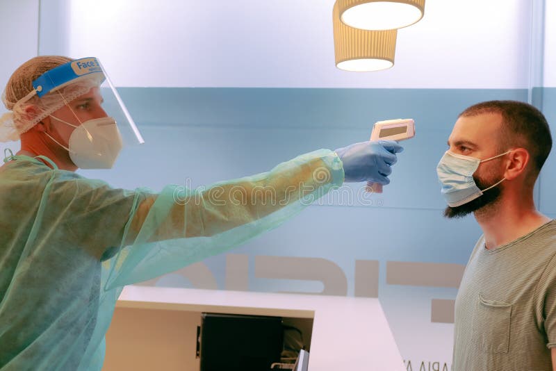 Profile View of Man Measuring Customer Temperature at Modern Clinic ...